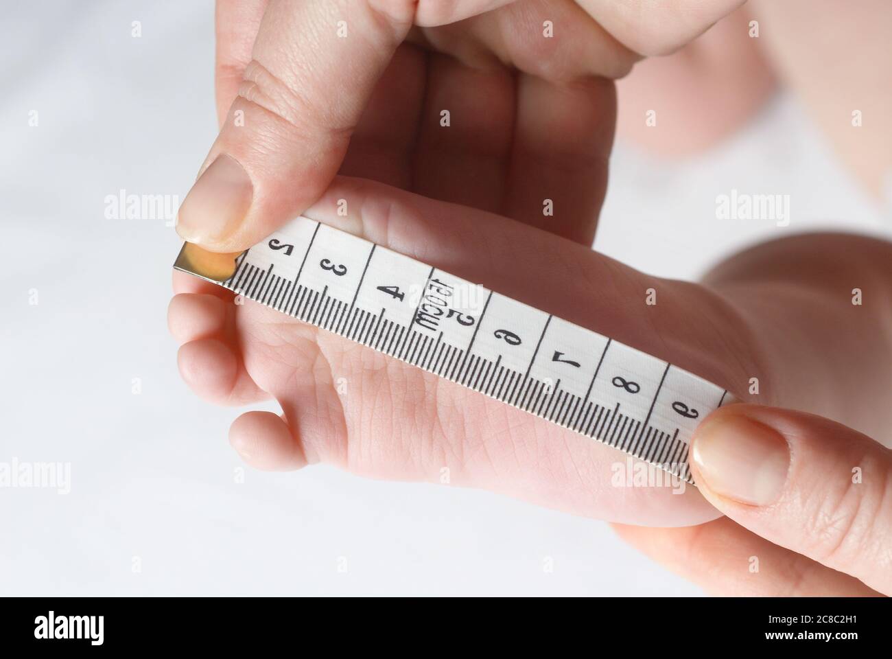 Adult measuring foot of baby close up of hands Stock Photo - Alamy