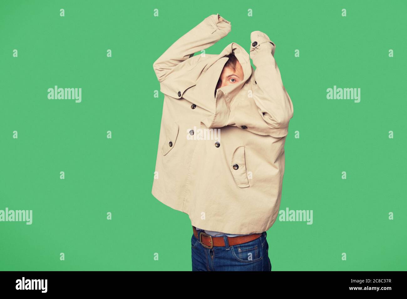 Young man wearing jacket while looking from jacket over green ...