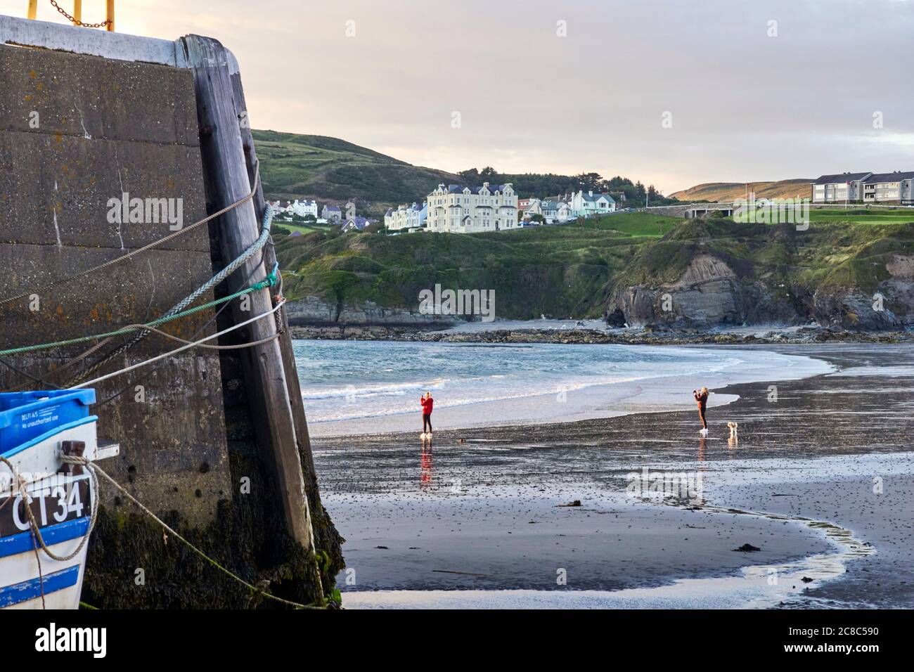 Two women taking photos of the sunset at Port Erin beach at low tide ...