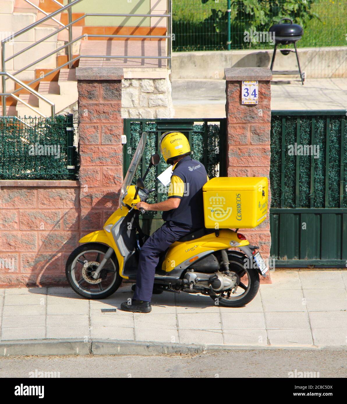 Postman from the Spanish post office Correos delivering post from a ...