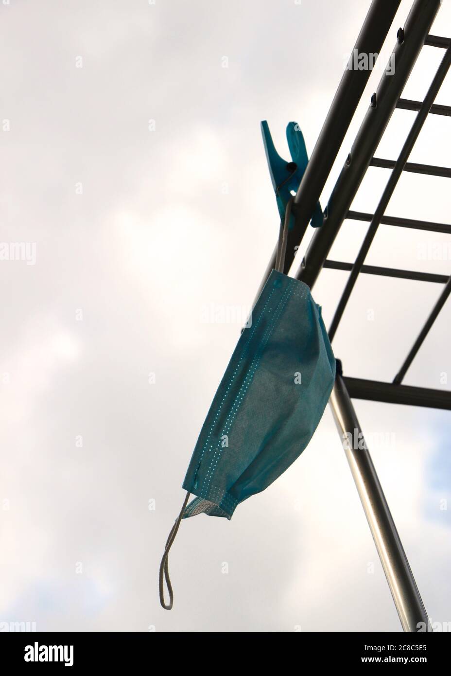 Blue and white washed medical face mask hanging drying on an aluminium ...