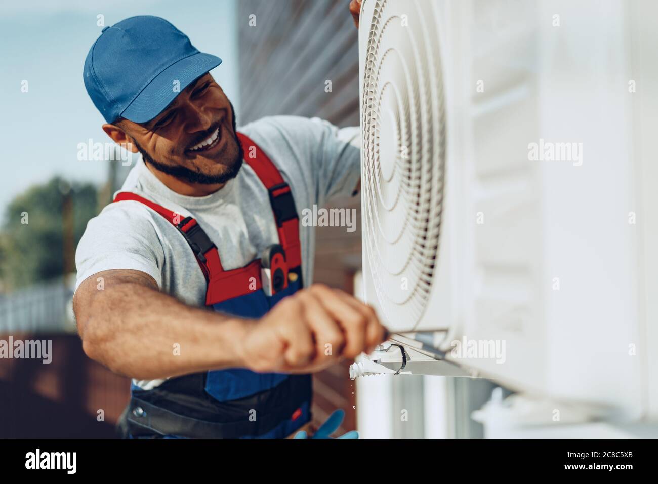 Young black man repairman checking an outside air conditioner unit ...