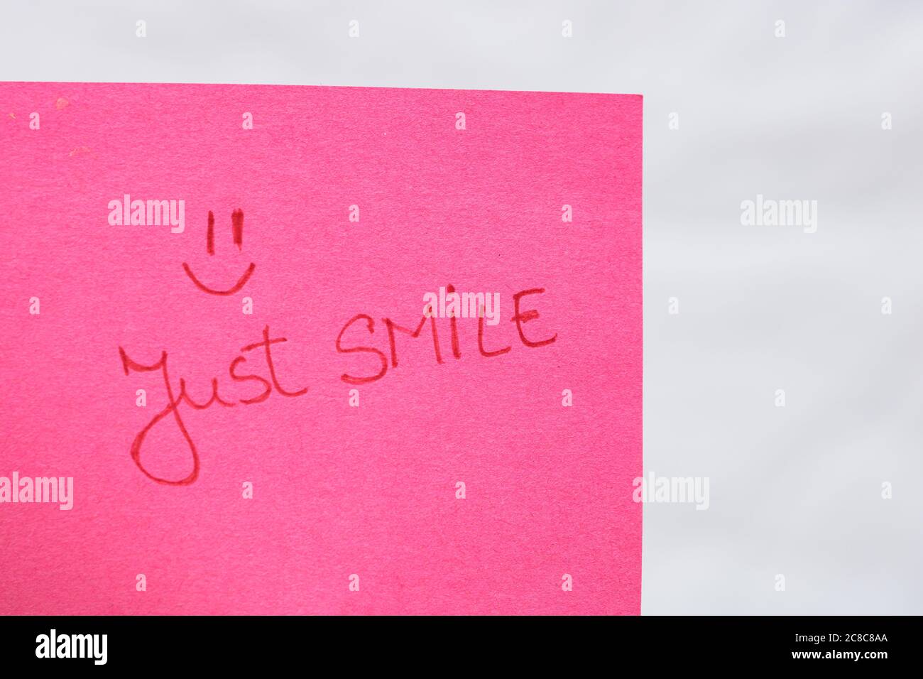 Just smile handwriting text close up isolated on pink paper with copy ...