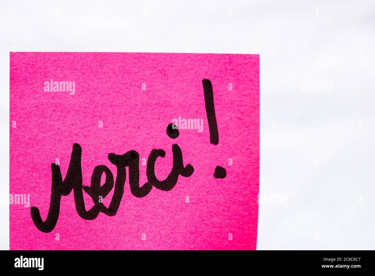 Merci handwriting text close up isolated on pink paper with copy space ...