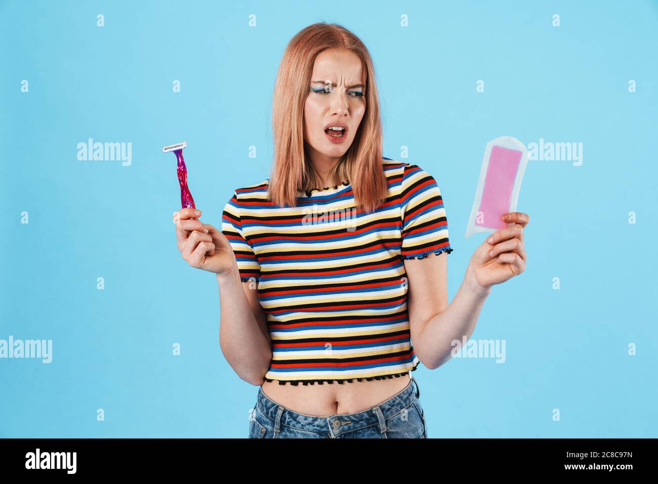 Image of beautiful displeased woman holding razor and wax strip ...