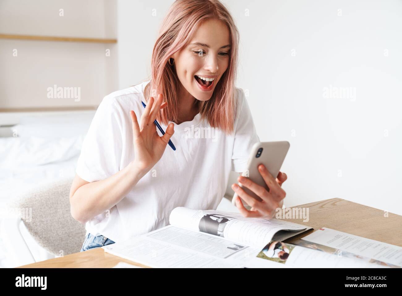 Image of smiling caucasian woman using smartphone and waving hand while ...