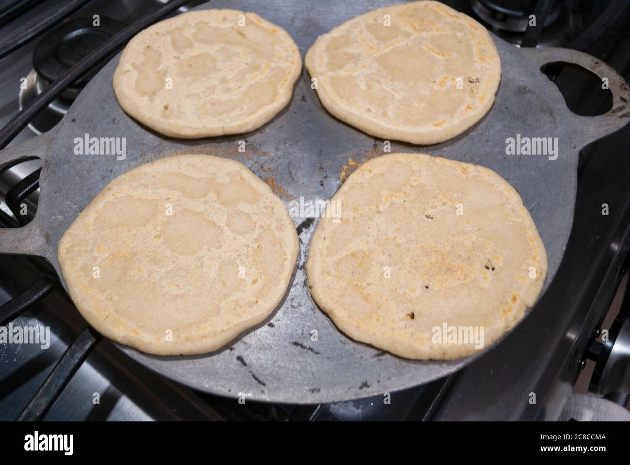 Nutritious handmade corn tortilla cooked on a metal griddle on a gas ...