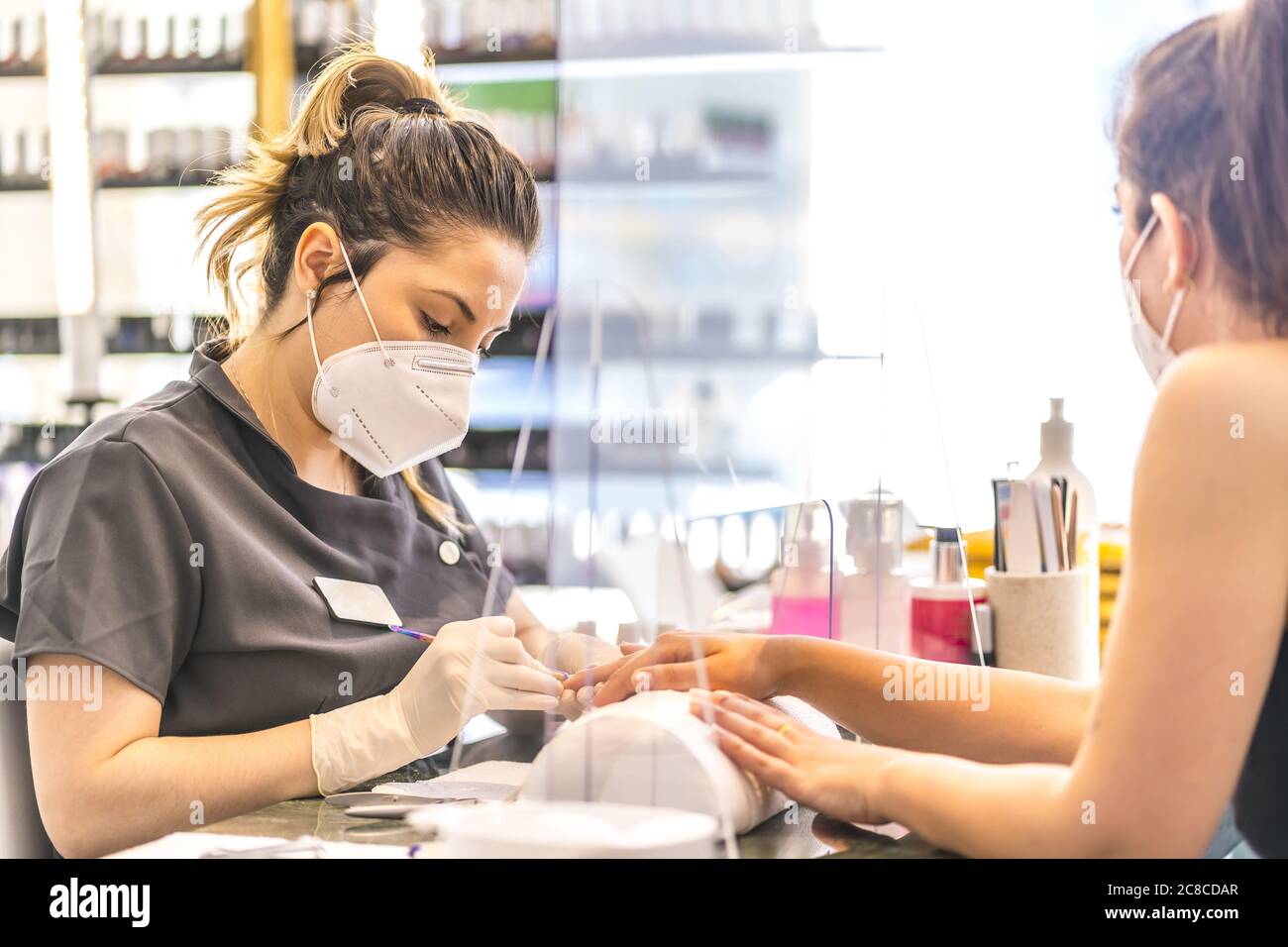 Shallow focus shot of a Hispanic female nail artist wearing a face mask ...