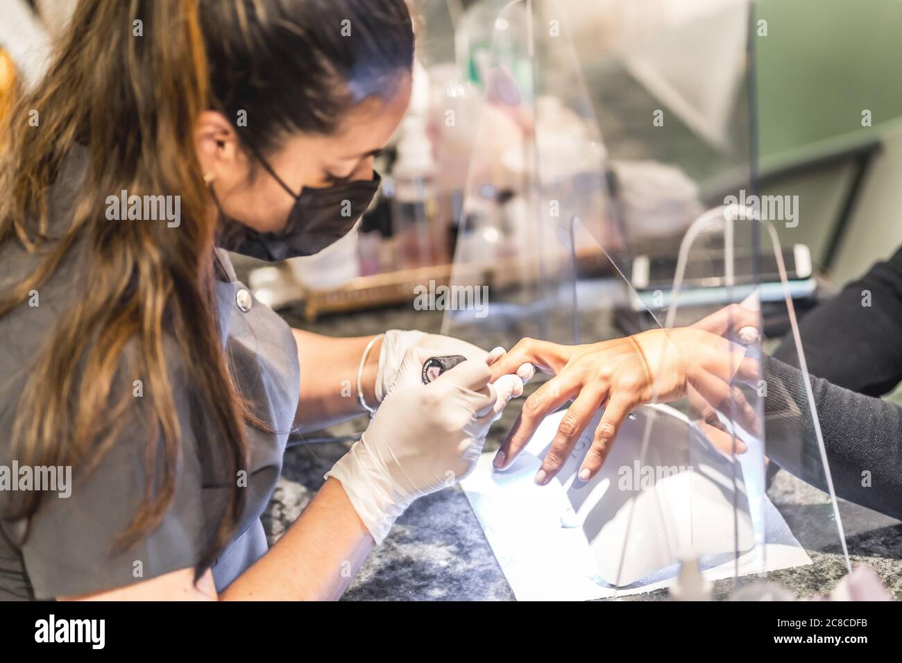 Shallow focus shot of a Hispanic female nail artist wearing a face mask ...