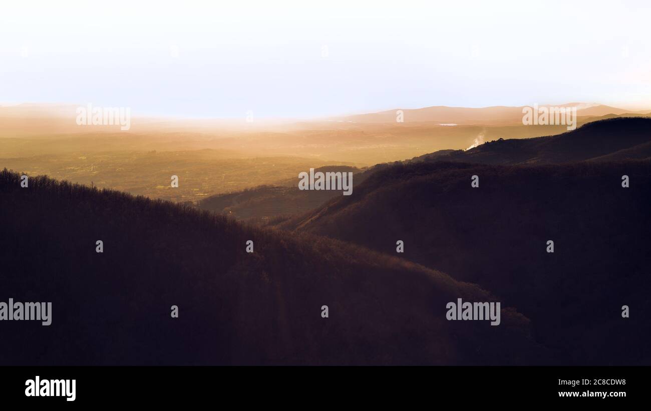 Landscape shot of beautiful hills covered in forests during the sunset ...