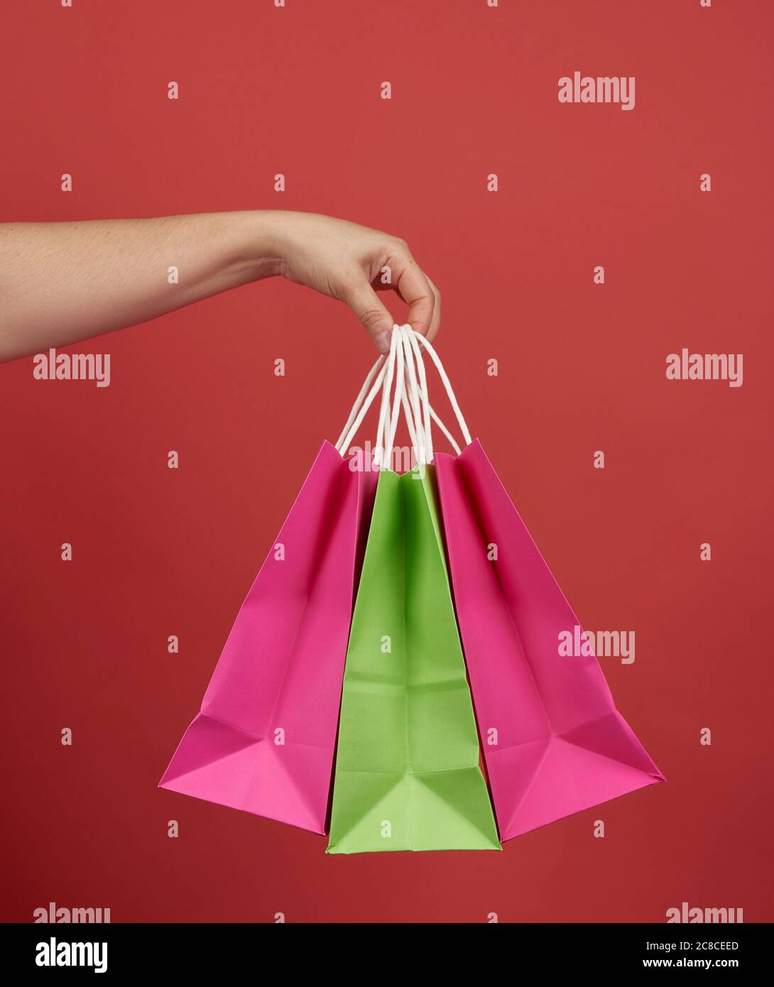 woman holds stack of paper bags on red background, shopping concept ...