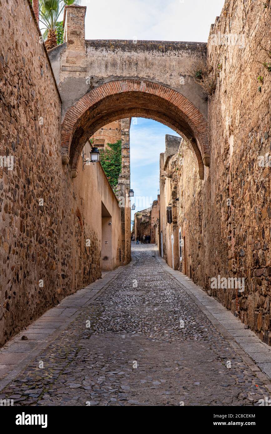 Narrow alley with old stone buildings at Caceres, Extremadura, Spain. A ...