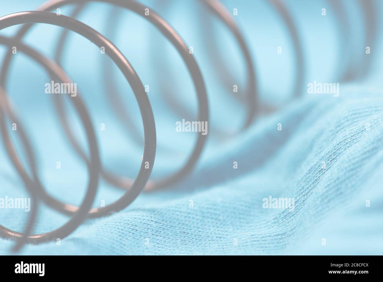 Details of a metal spring on blue cloth Stock Photo - Alamy