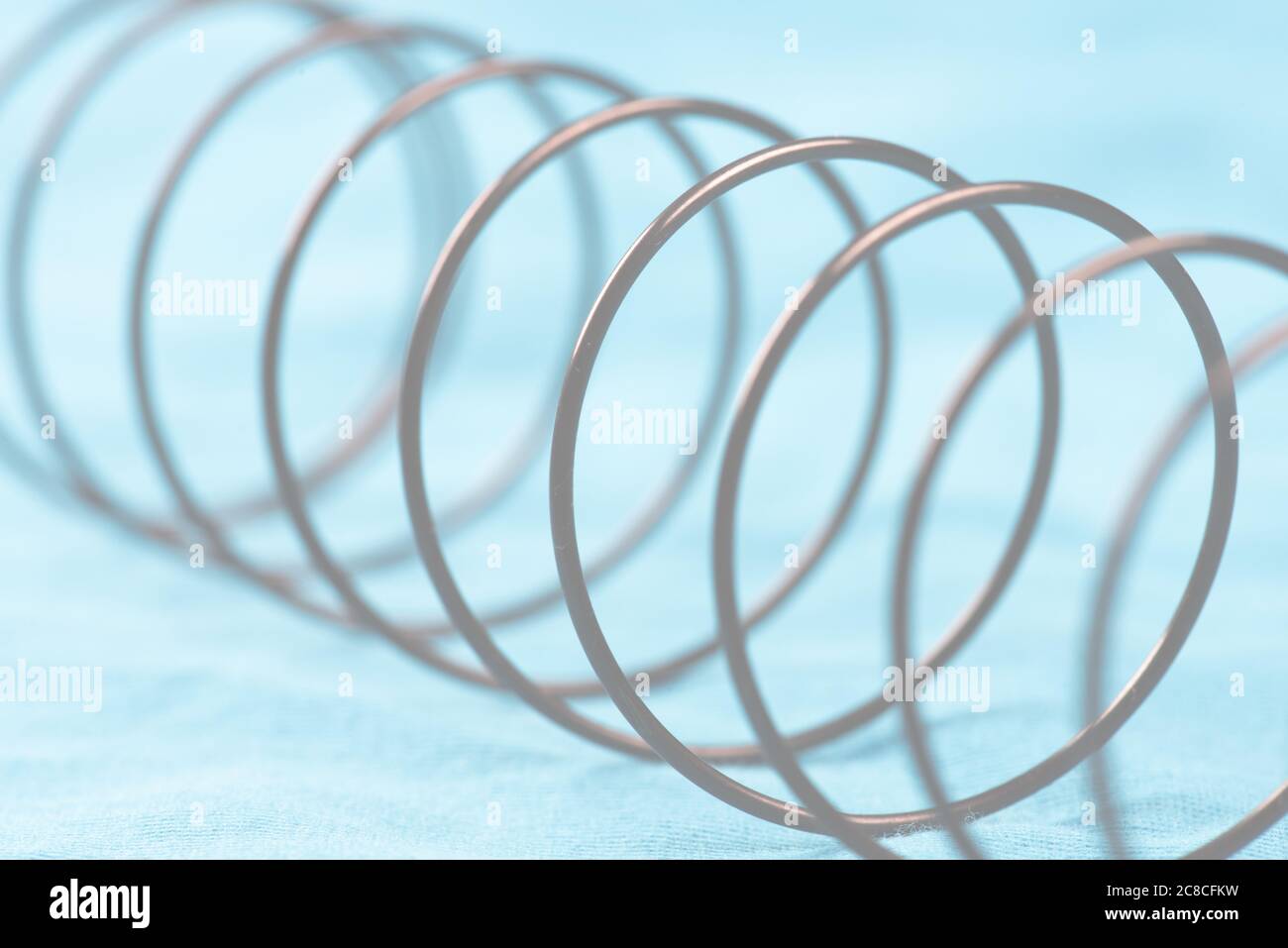 Details of a metal spring on blue cloth Stock Photo - Alamy