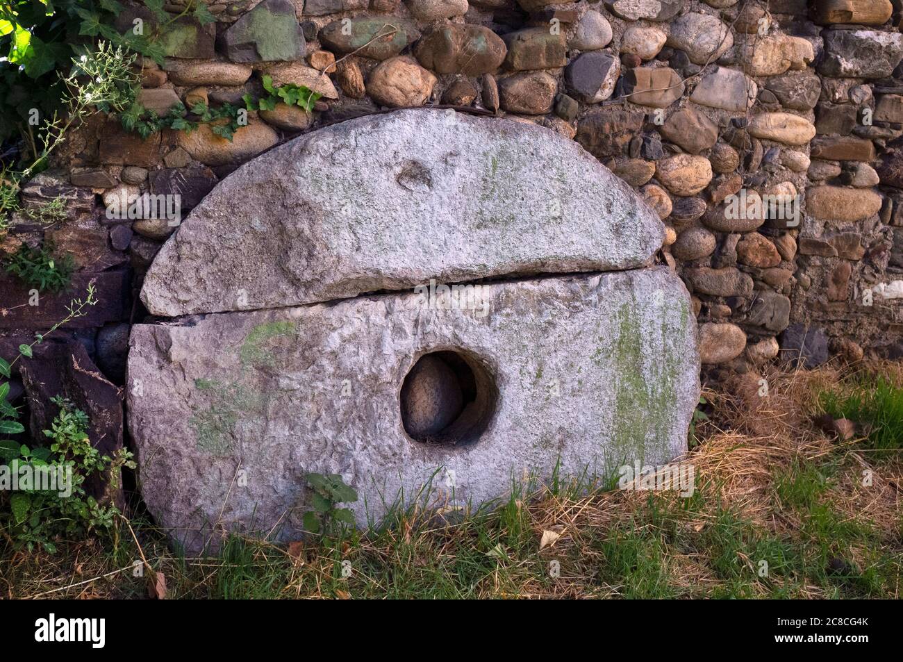An old mill stone rests against a wall in the French village of ...