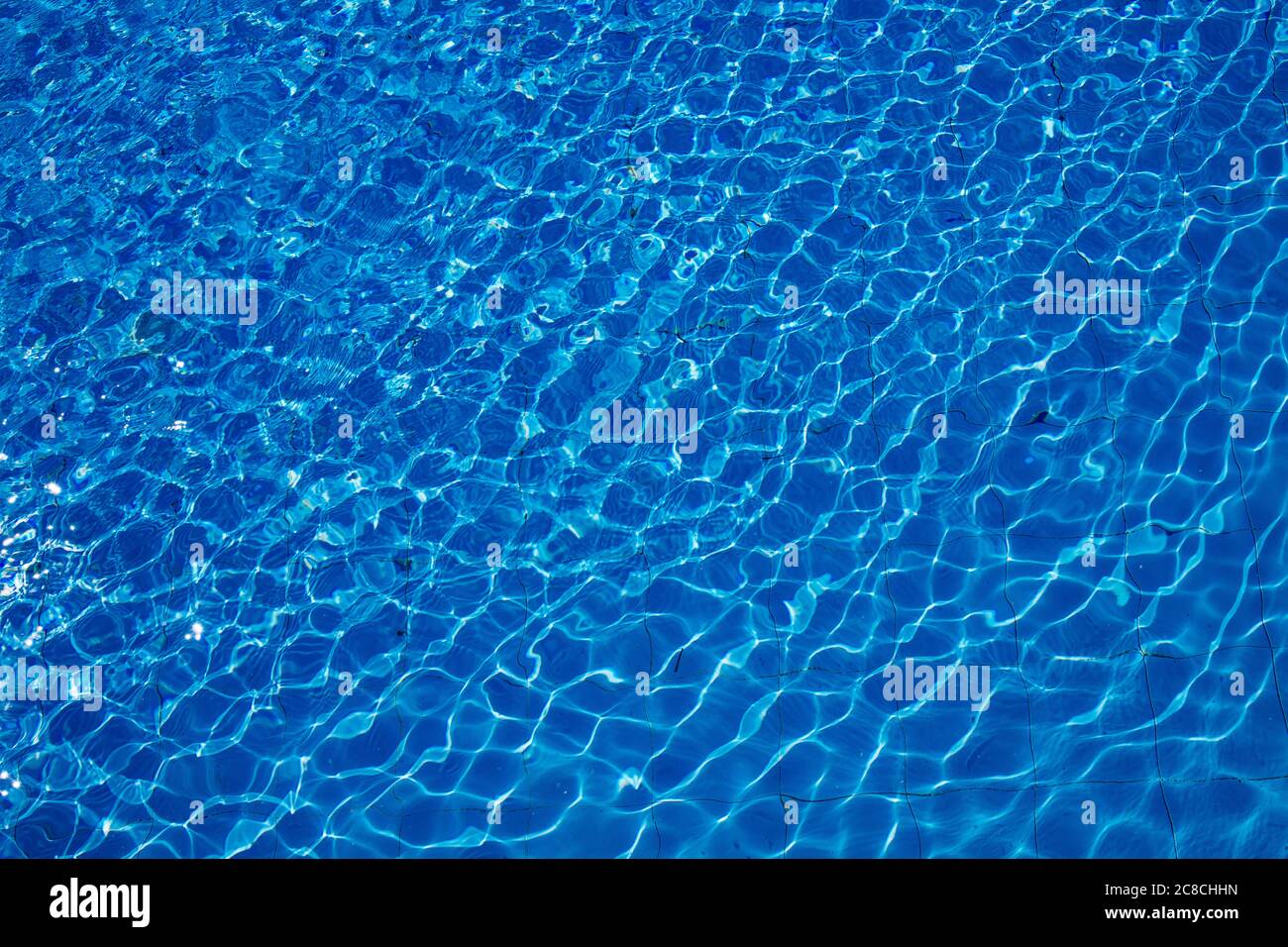Swimming pool, blue clear water in the outdoor pool, with sun flare on ...
