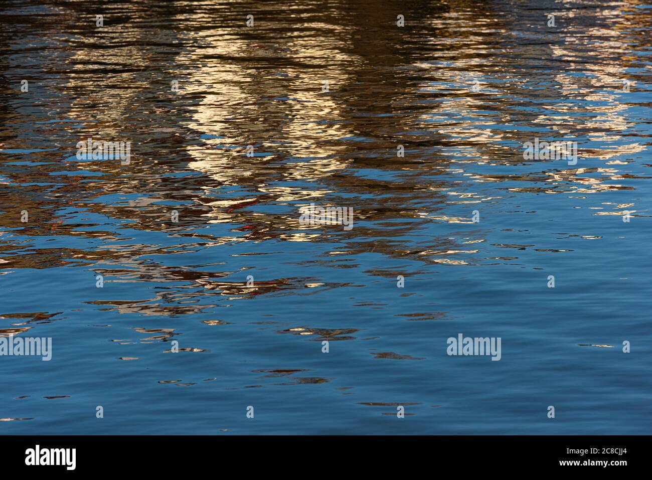 Water with small waves. Reflections of blue sky and buildings Stock ...