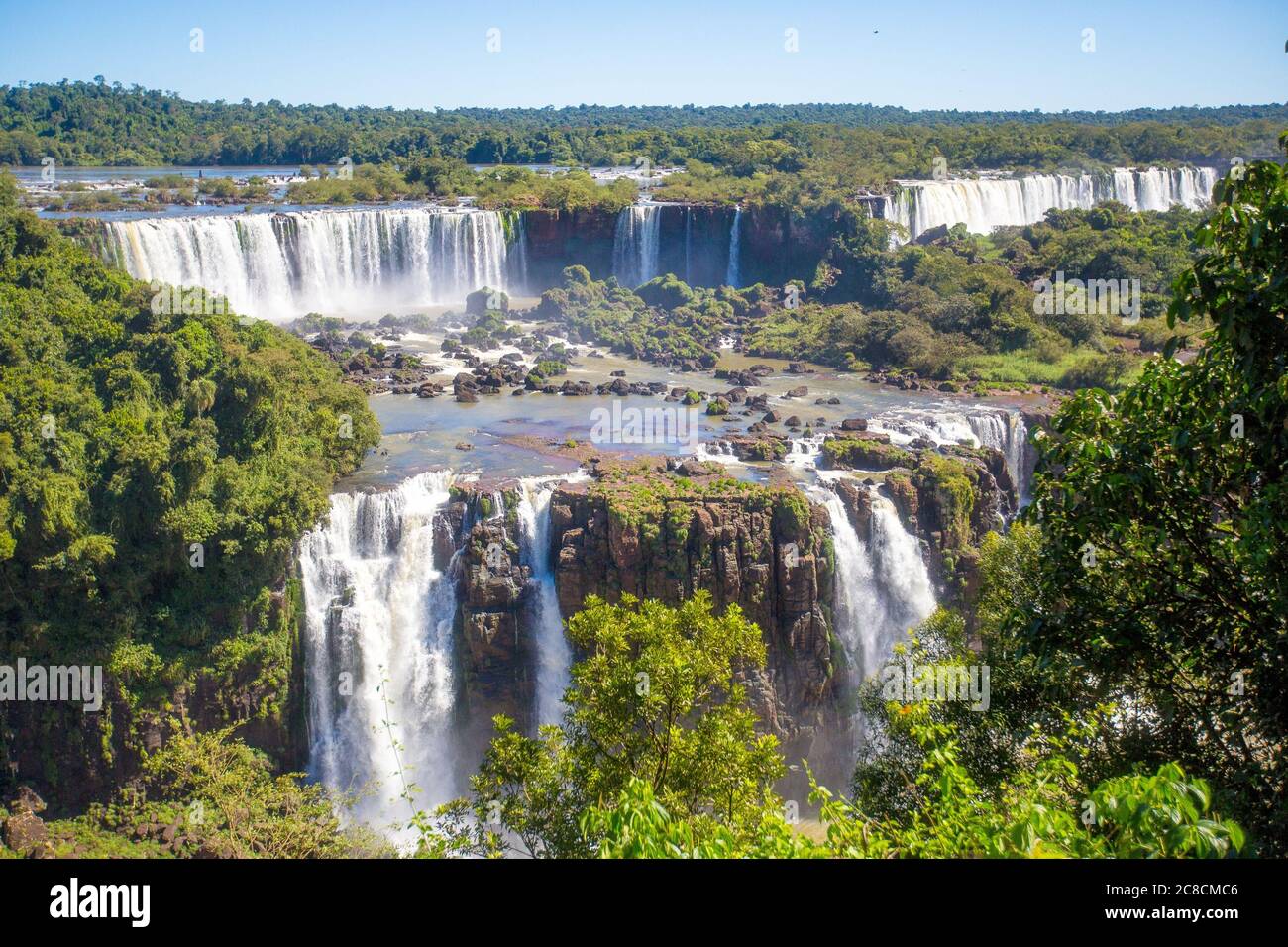 Iguazu Falls in Brazil surrounded by trees under the blue sky Stock ...