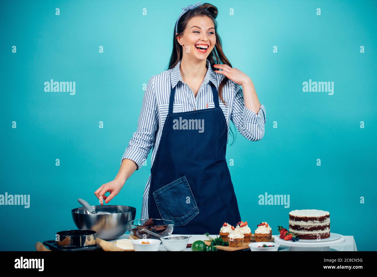 Happy young bakery woman having fun while decorating delicious cake in ...
