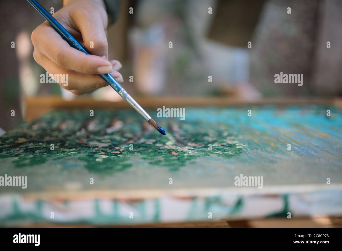 Close-up view of hand holding used paint brush over painting Stock ...