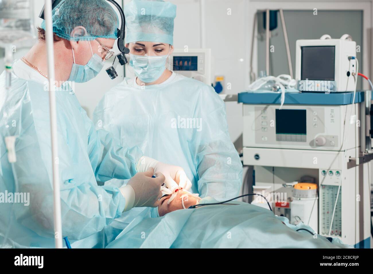 Surgeon performing cosmetic surgery on nose in hospital operating room ...