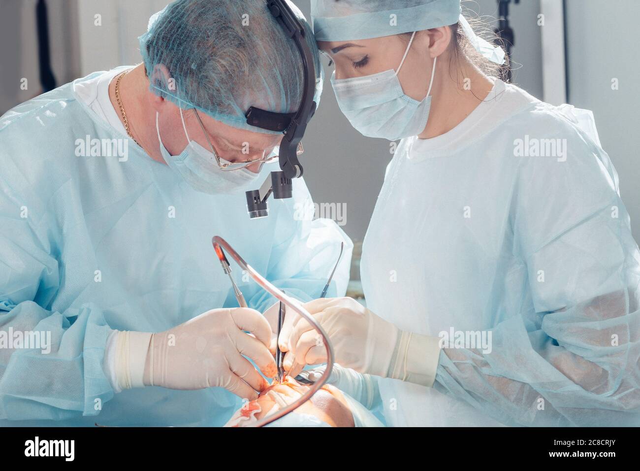 Surgeon performing cosmetic surgery on nose in hospital operating room ...