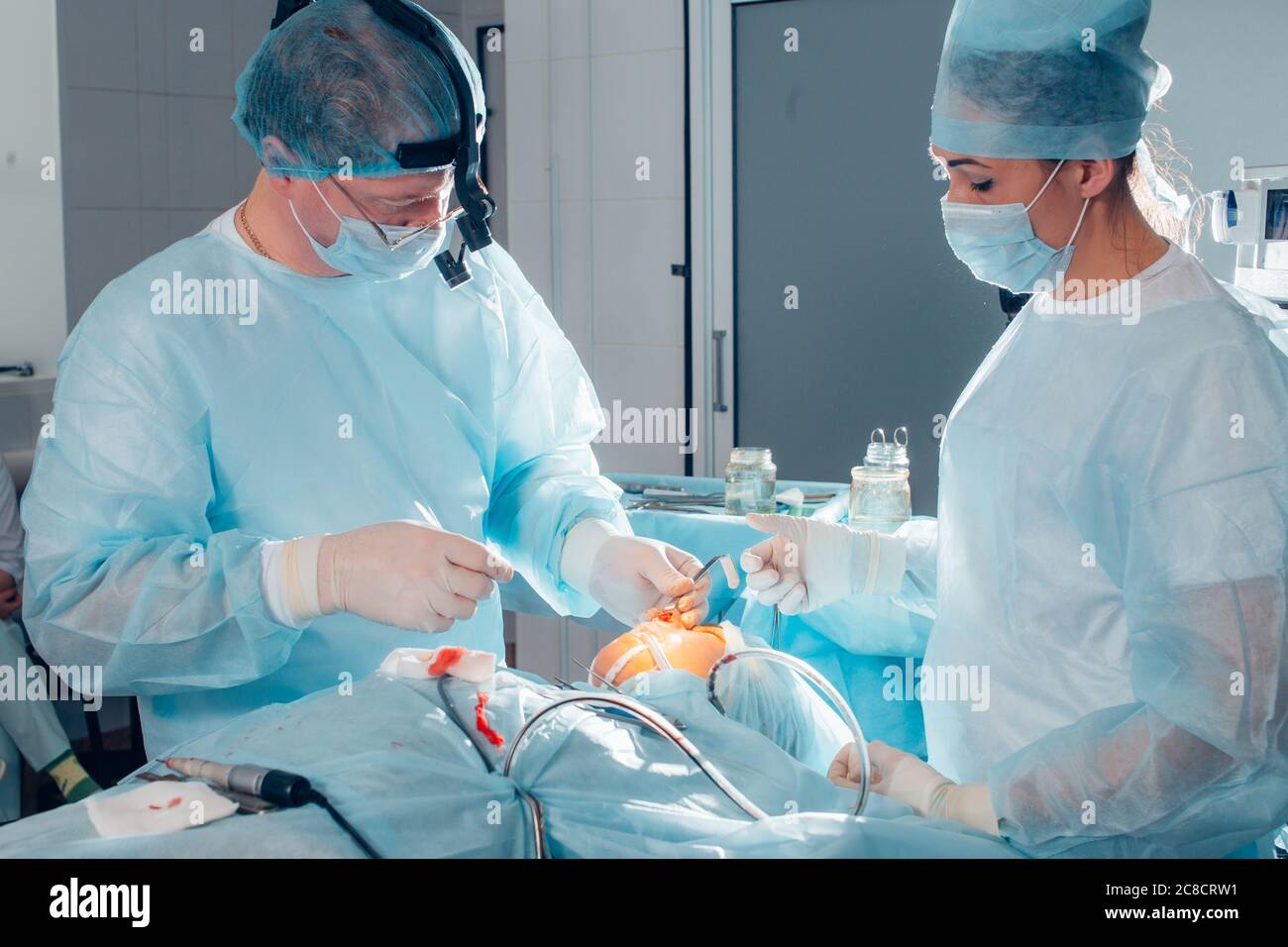 Surgeon performing cosmetic surgery on nose in hospital operating room ...