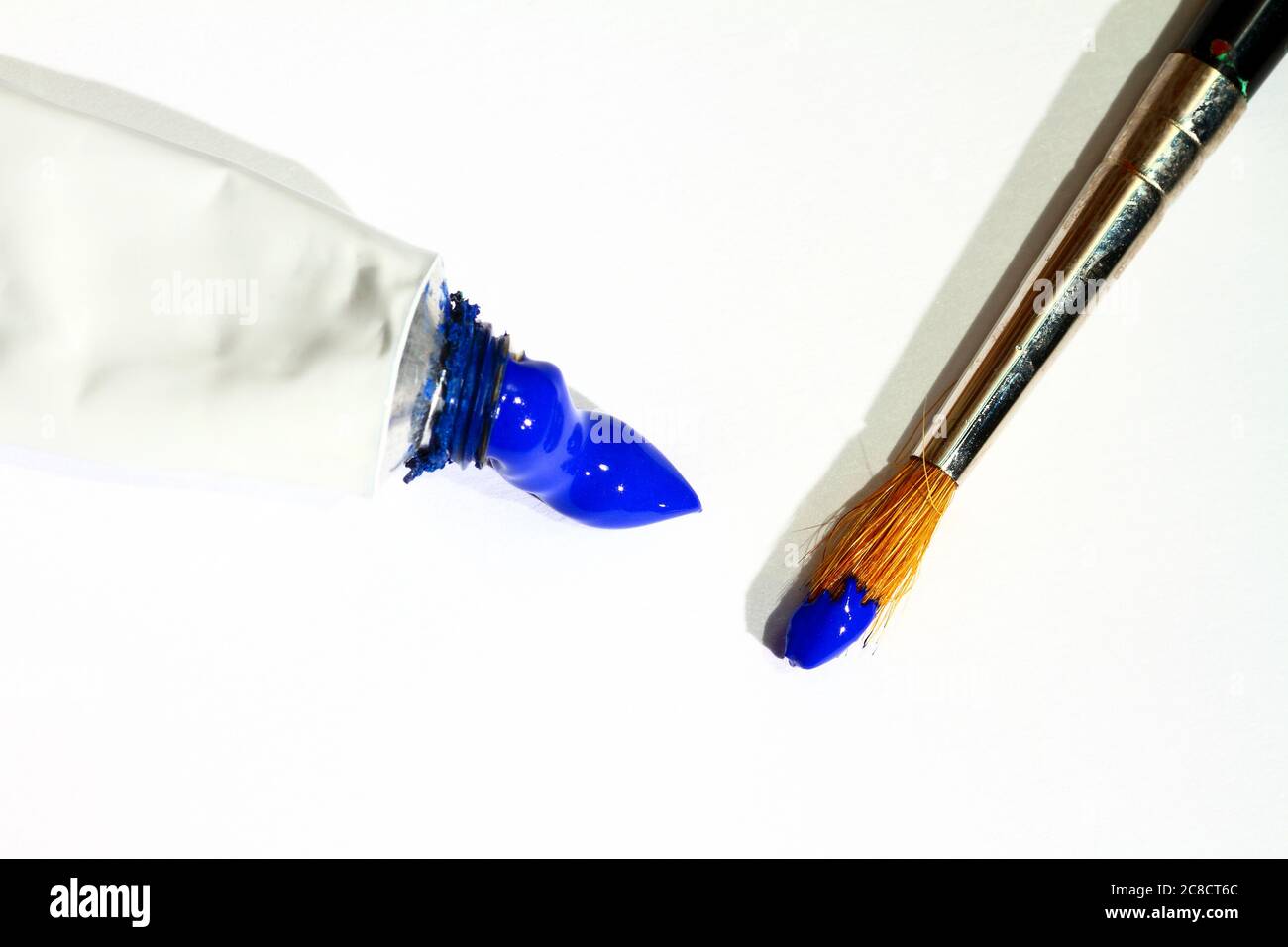 Artists paint brush and tube of blue paint isolated on a white ...