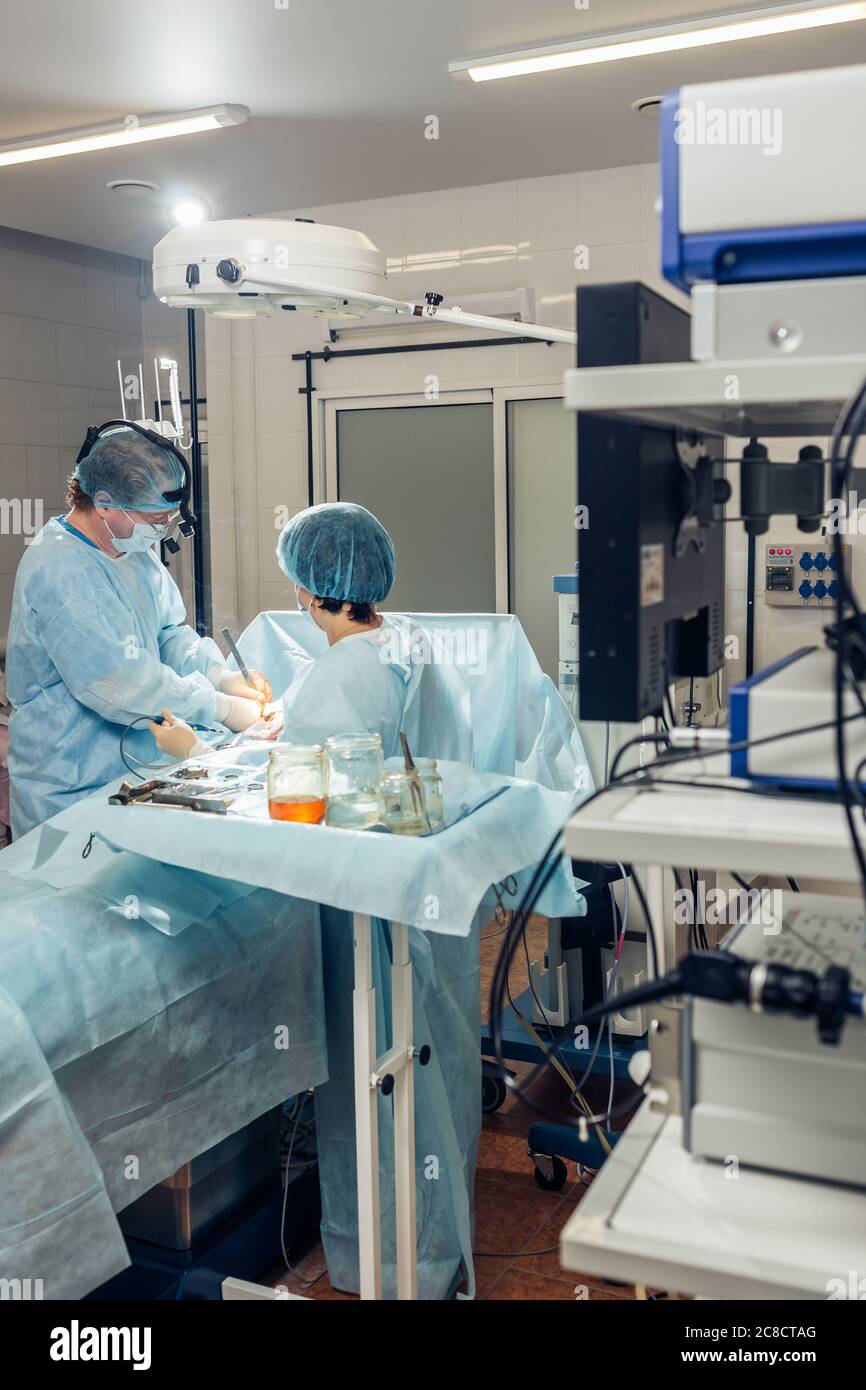 Wide view of a team of four surgeons operating on a patient in a dark ...