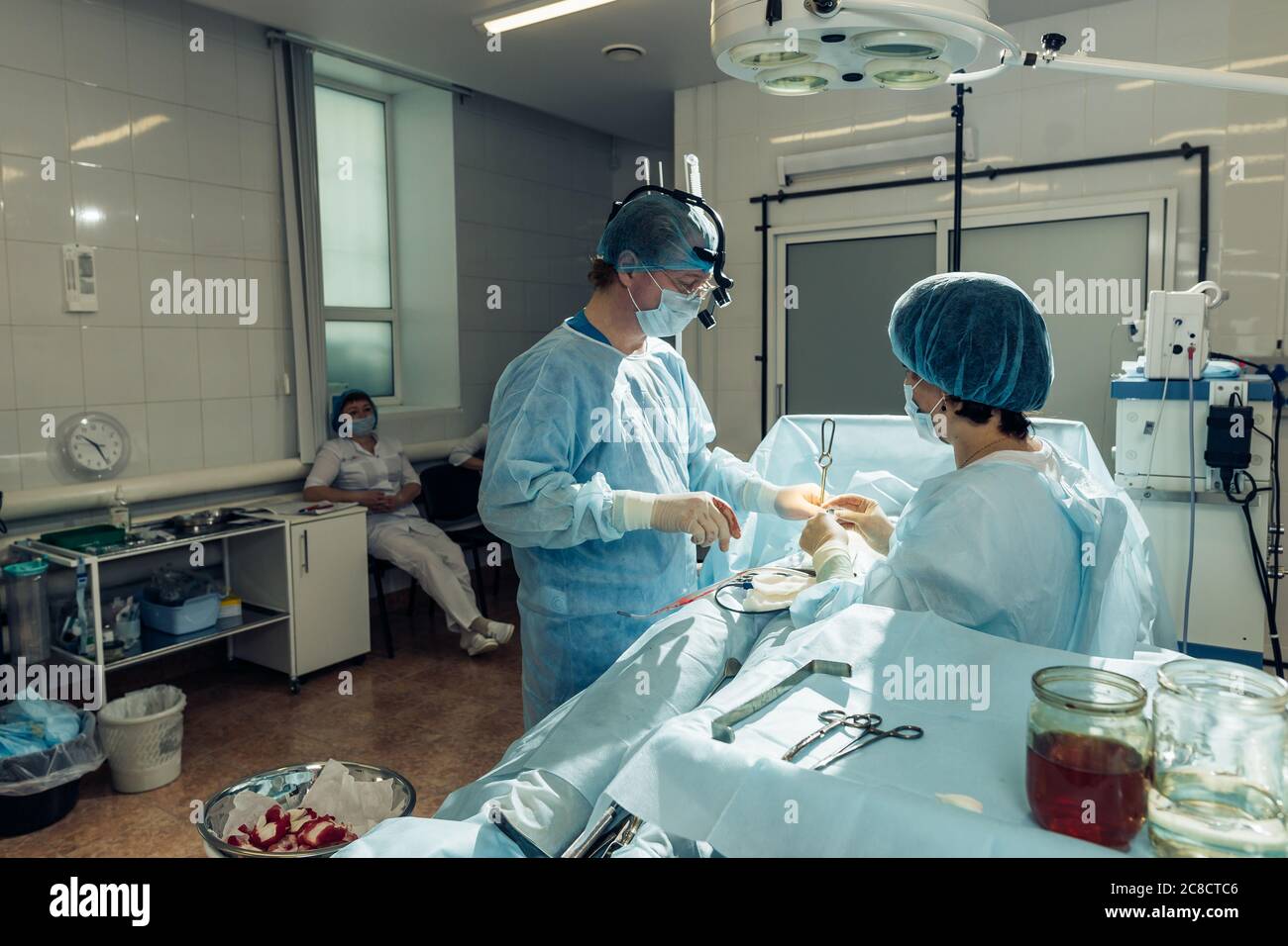 Wide view of a team of four surgeons operating on a patient in a dark ...