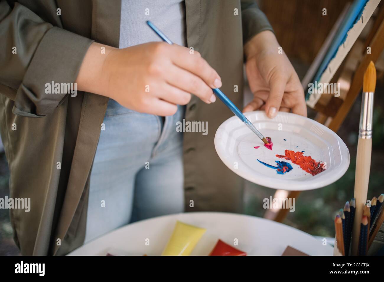 Woman's hands mixing paints in plate using brush Stock Photo - Alamy