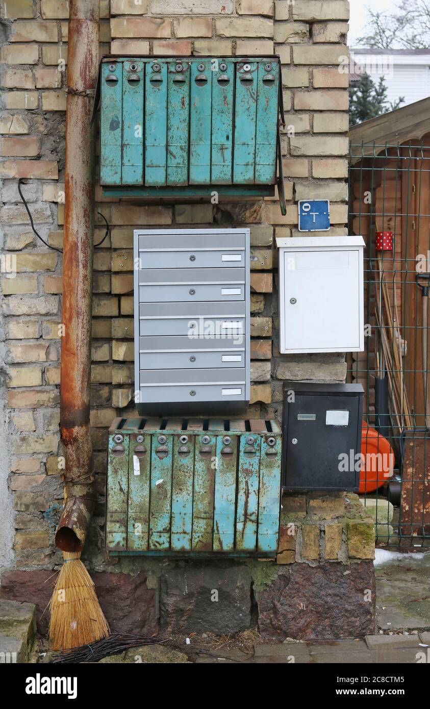 Old and new rusty mailboxes mounted on the wall of a yellow brick house ...