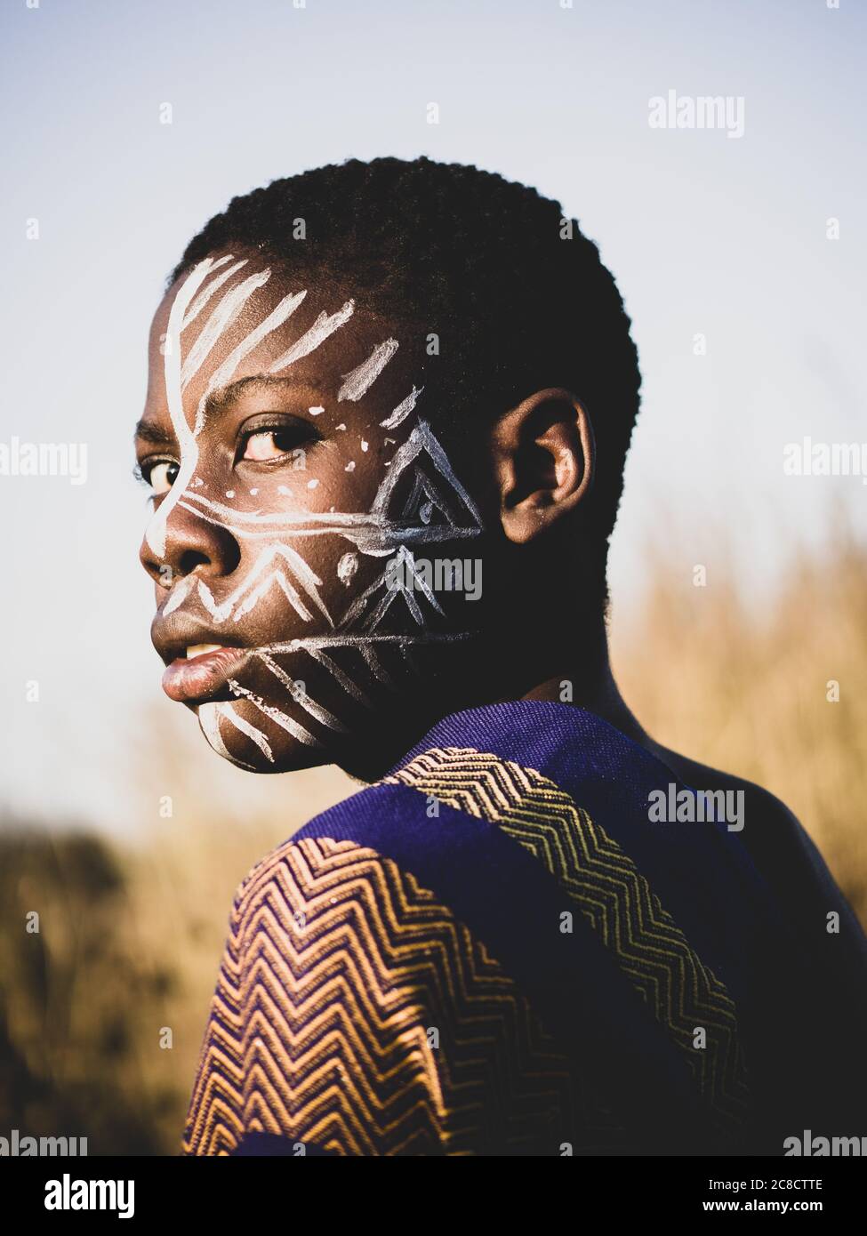portrait of an african boy with ethnic face paint and dressing in the ...