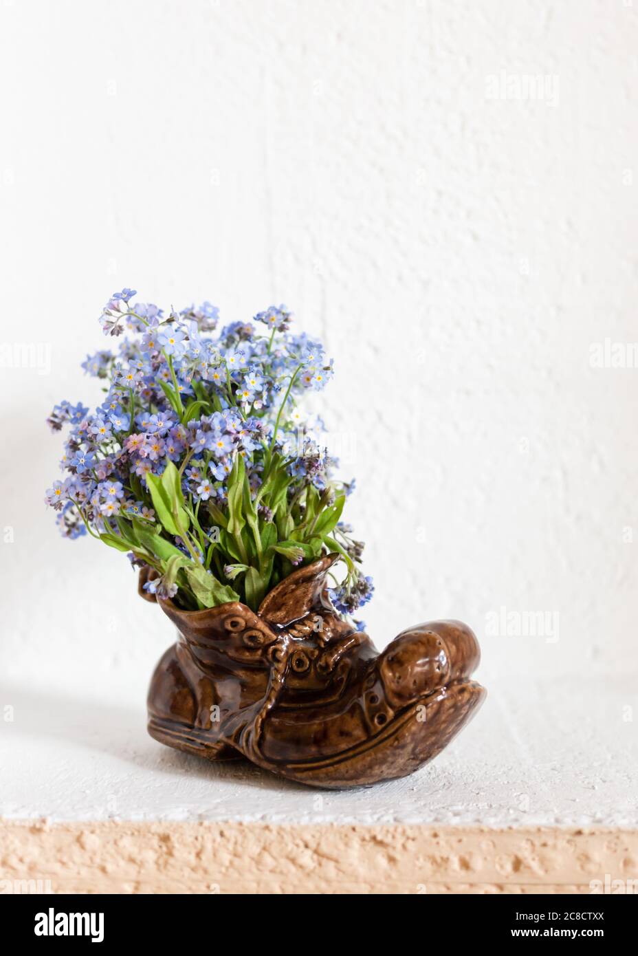 Ceramic slipper with a bouquet of forget-me-nots on a white background ...