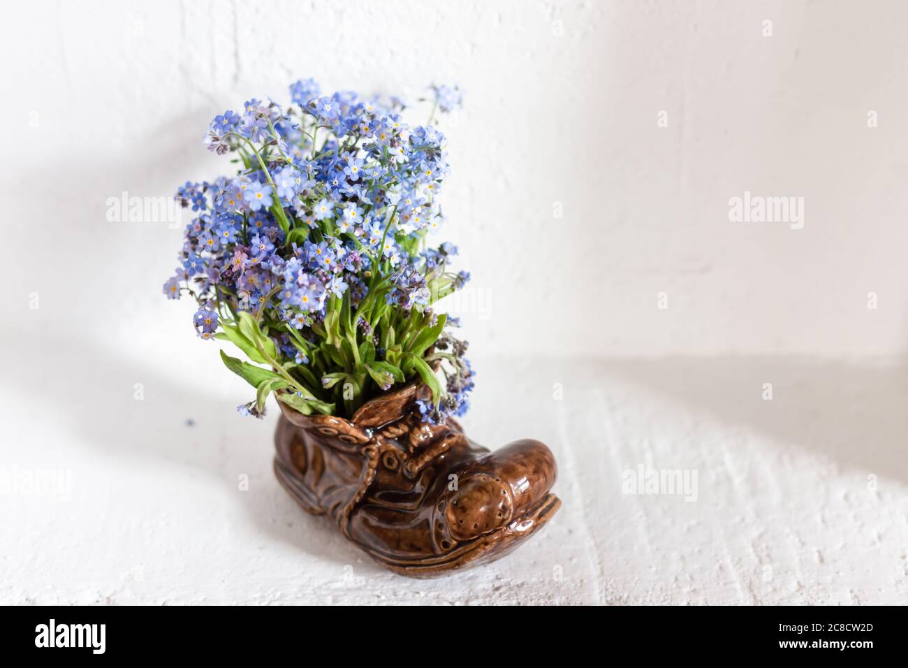 Ceramic slipper with a bouquet of forget-me-nots on a white background ...
