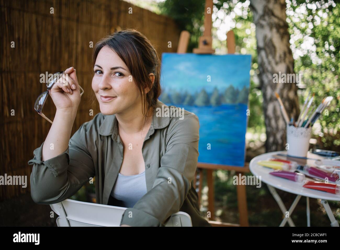 Happy artist holding glasses in art studio Stock Photo - Alamy