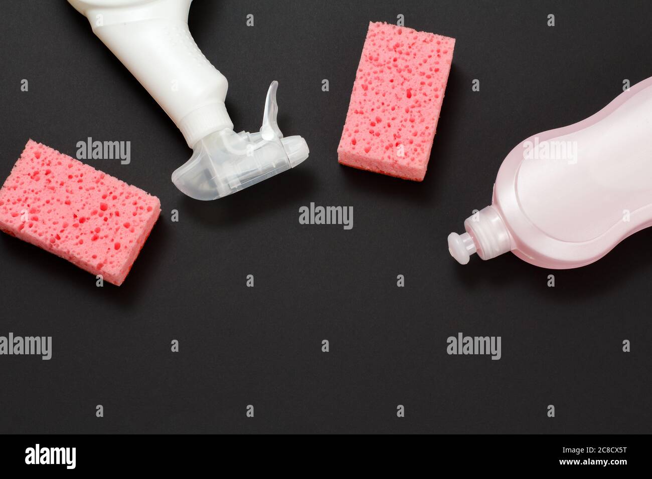 Plastic bottles of washing liquid and sponges on the black background ...
