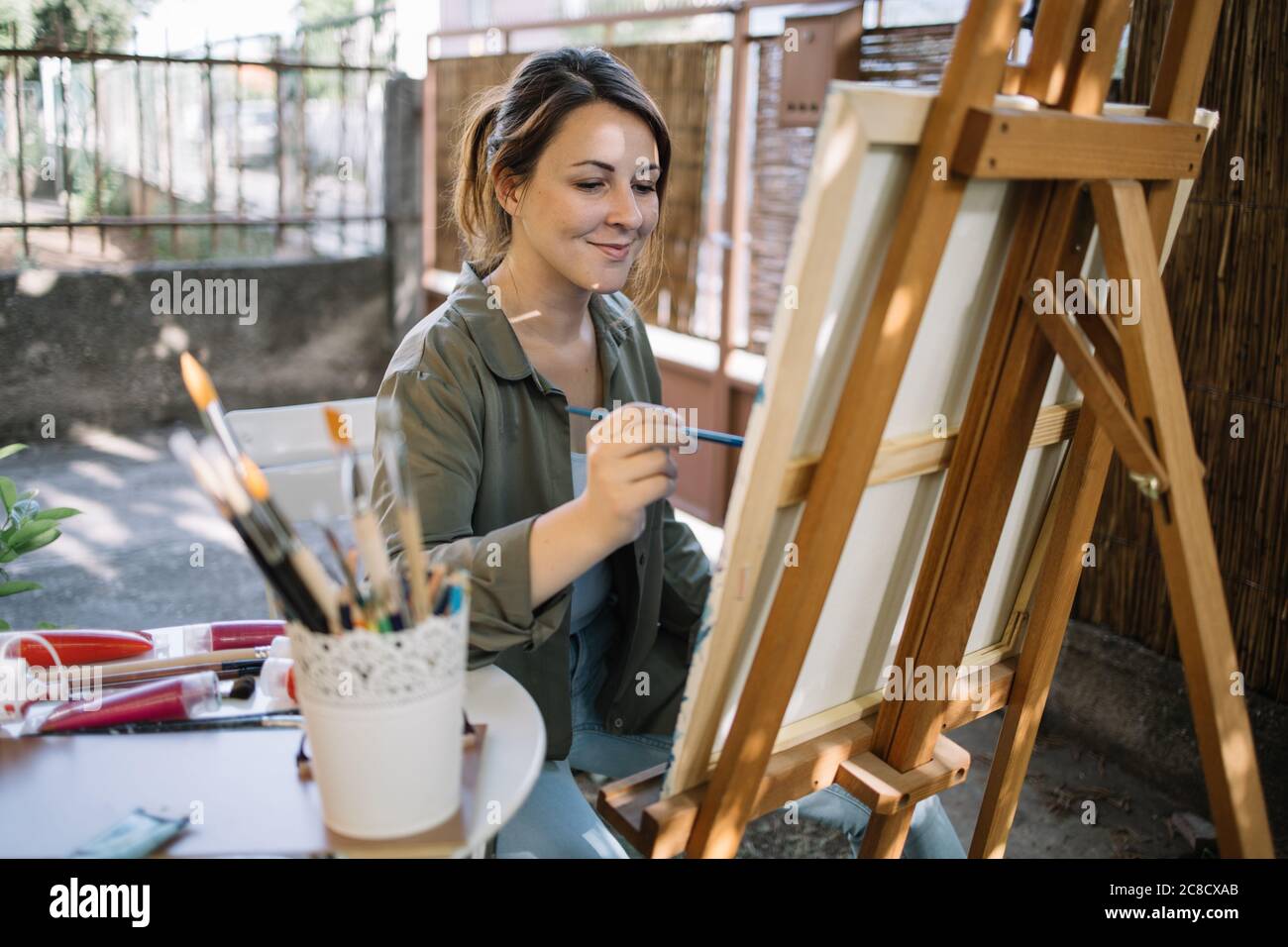 Smiling painter drawing picture using aquarelle paint and paintbrush ...