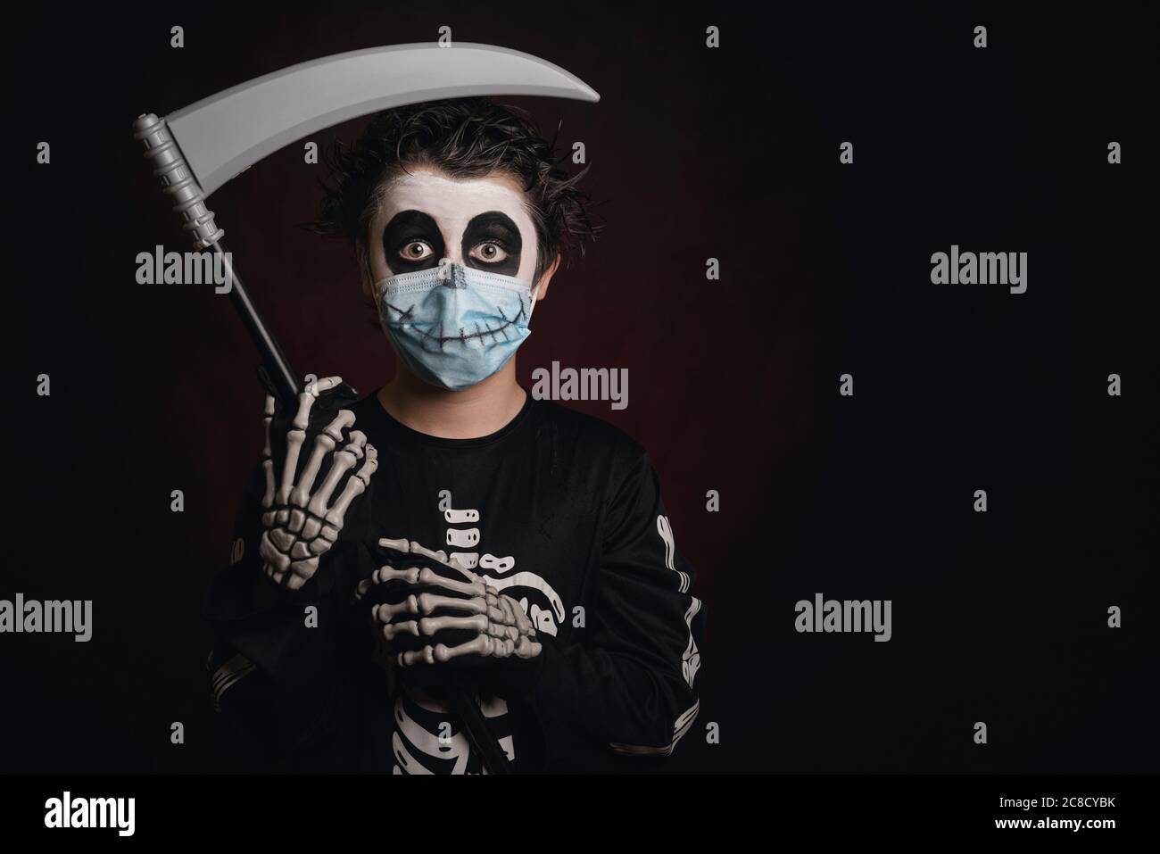 Happy Halloween. kid wearing medical mask in a skeleton costume with a ...