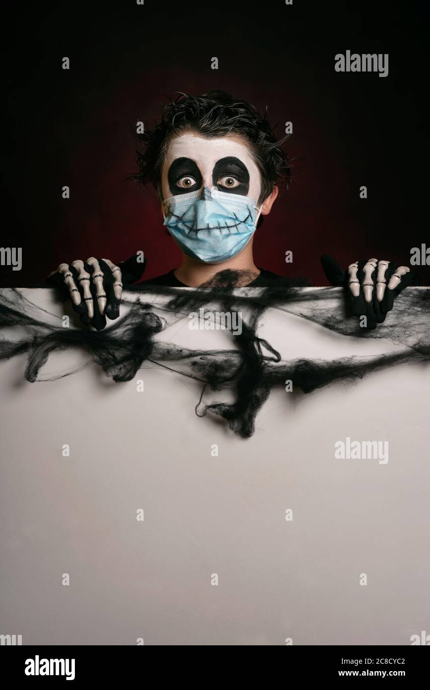 Happy Halloween. kid wearing medical mask in a skeleton costume holding ...