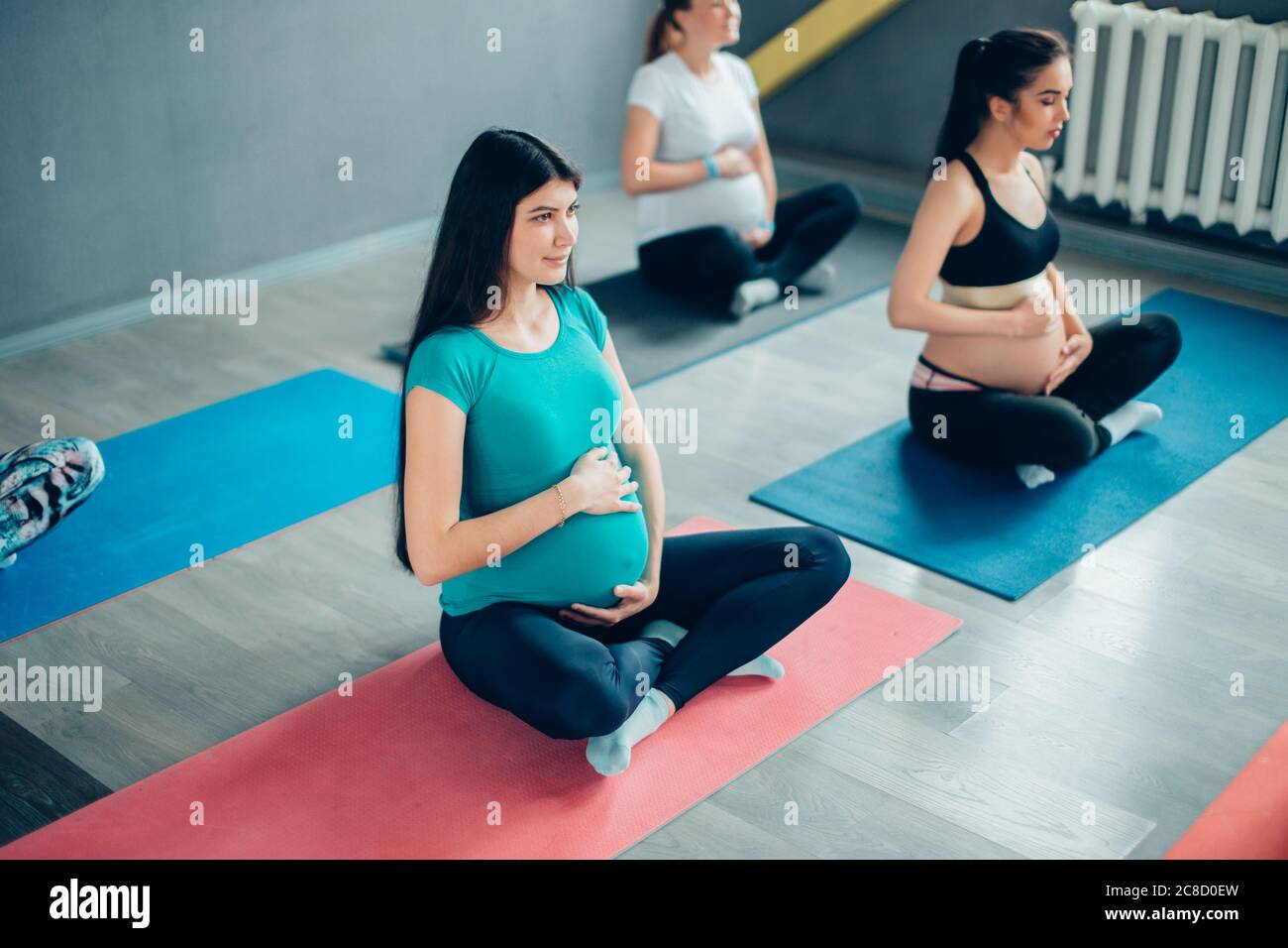 Group of young pregnant women doing relaxation exercise on exercising ...