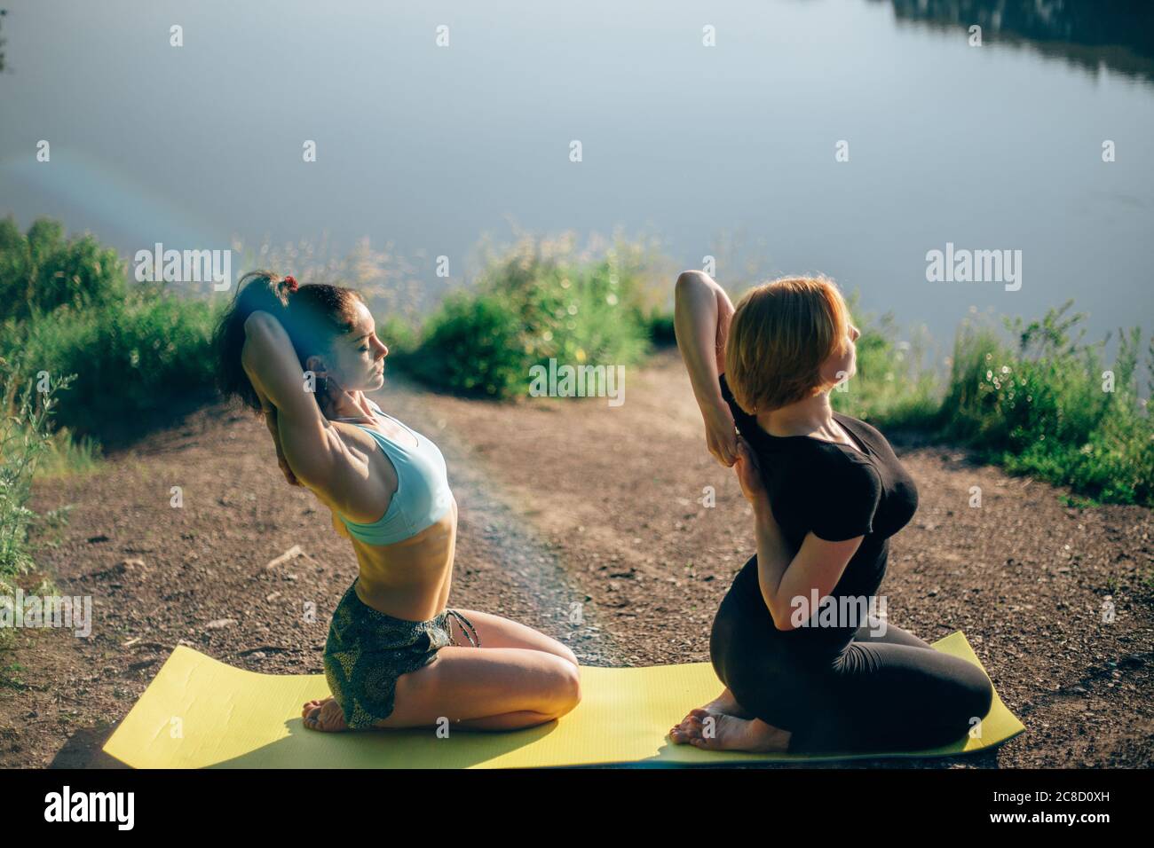 Two young women doing yoga asana half lord of the fishes pose. Ardha ...