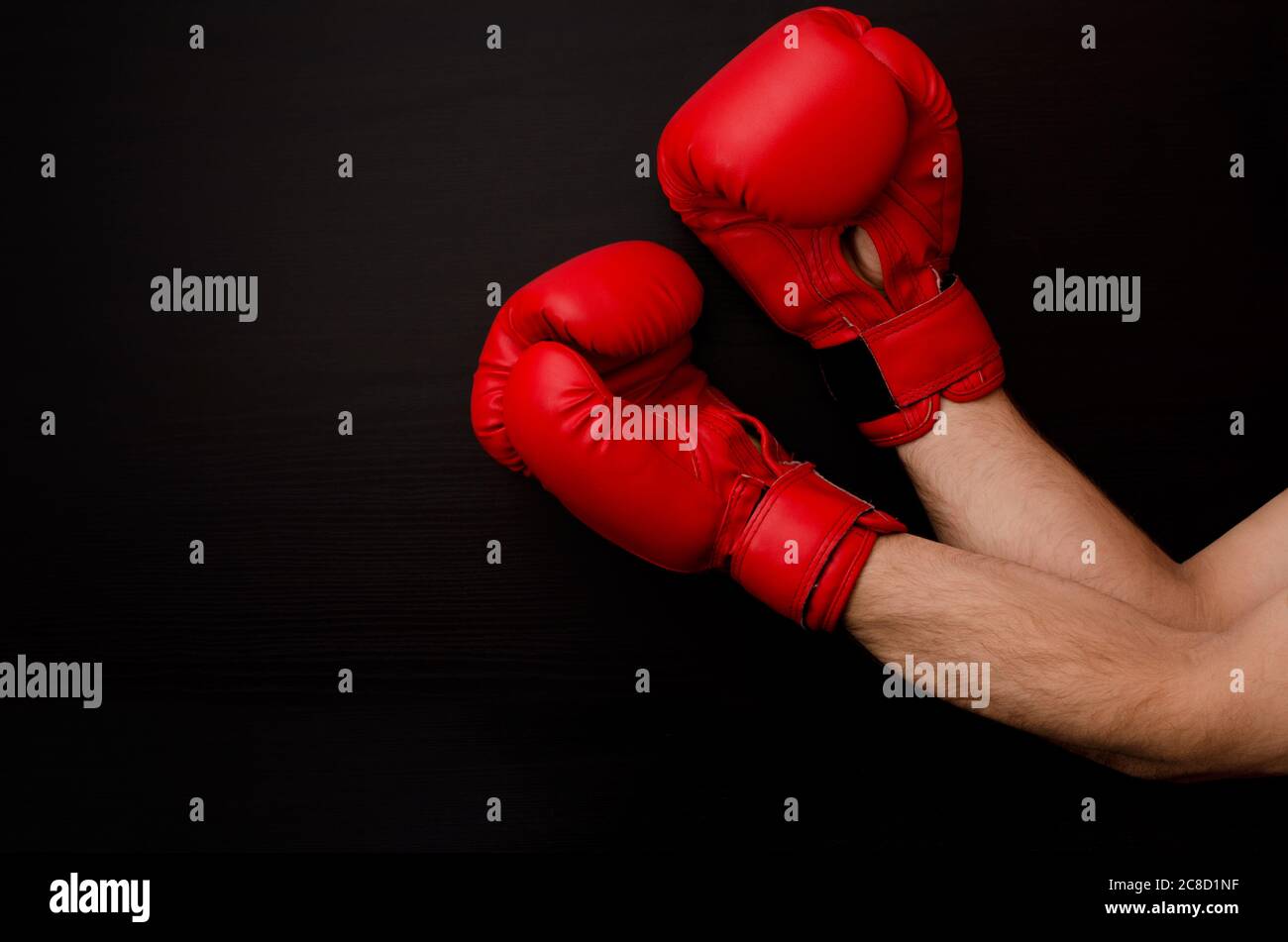 Hand in red boxing gloves in the corner of the frame on a black ...