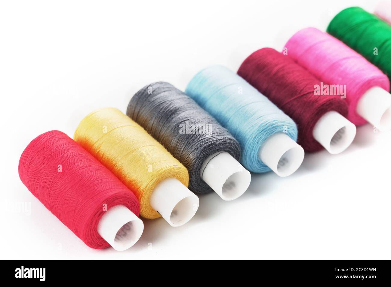 Sewing threads of different colors on reels on a white background. Free ...