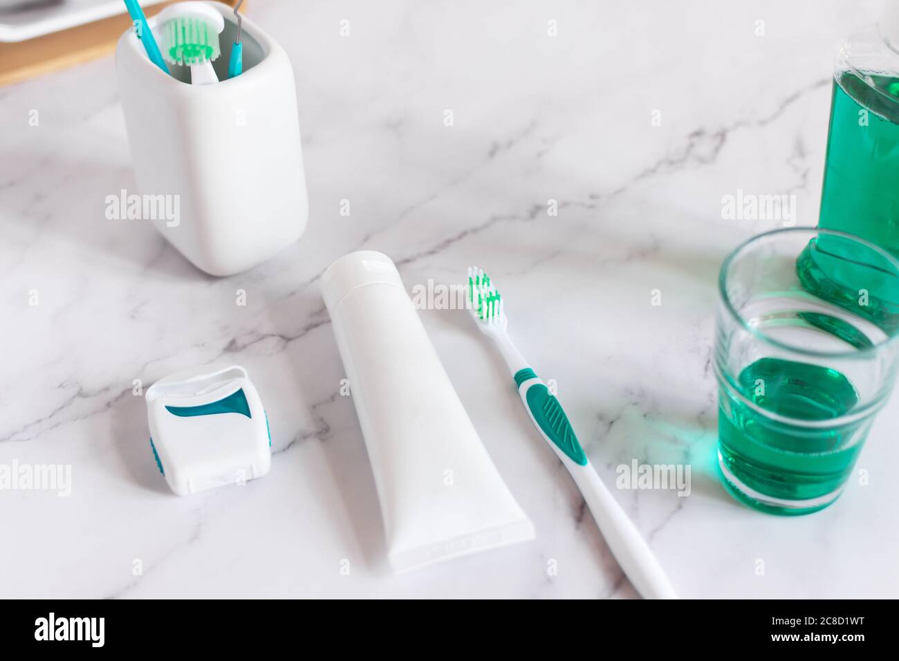Toothbrush, toothpaste, mouthwash and dental floss on white marble ...