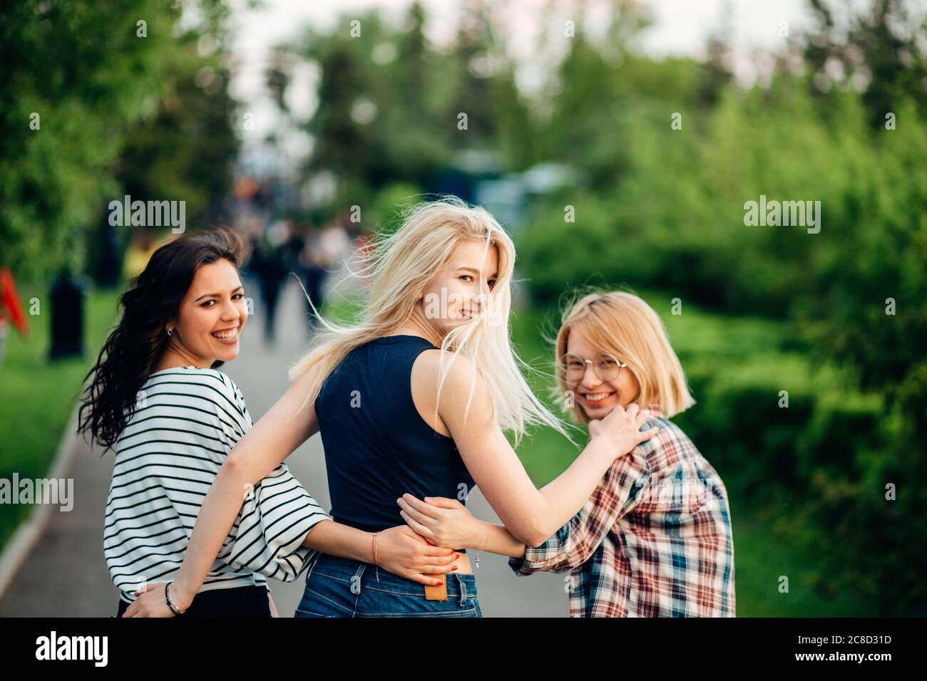 three girls having fun in the sunset park. rear view Stock Photo - Alamy