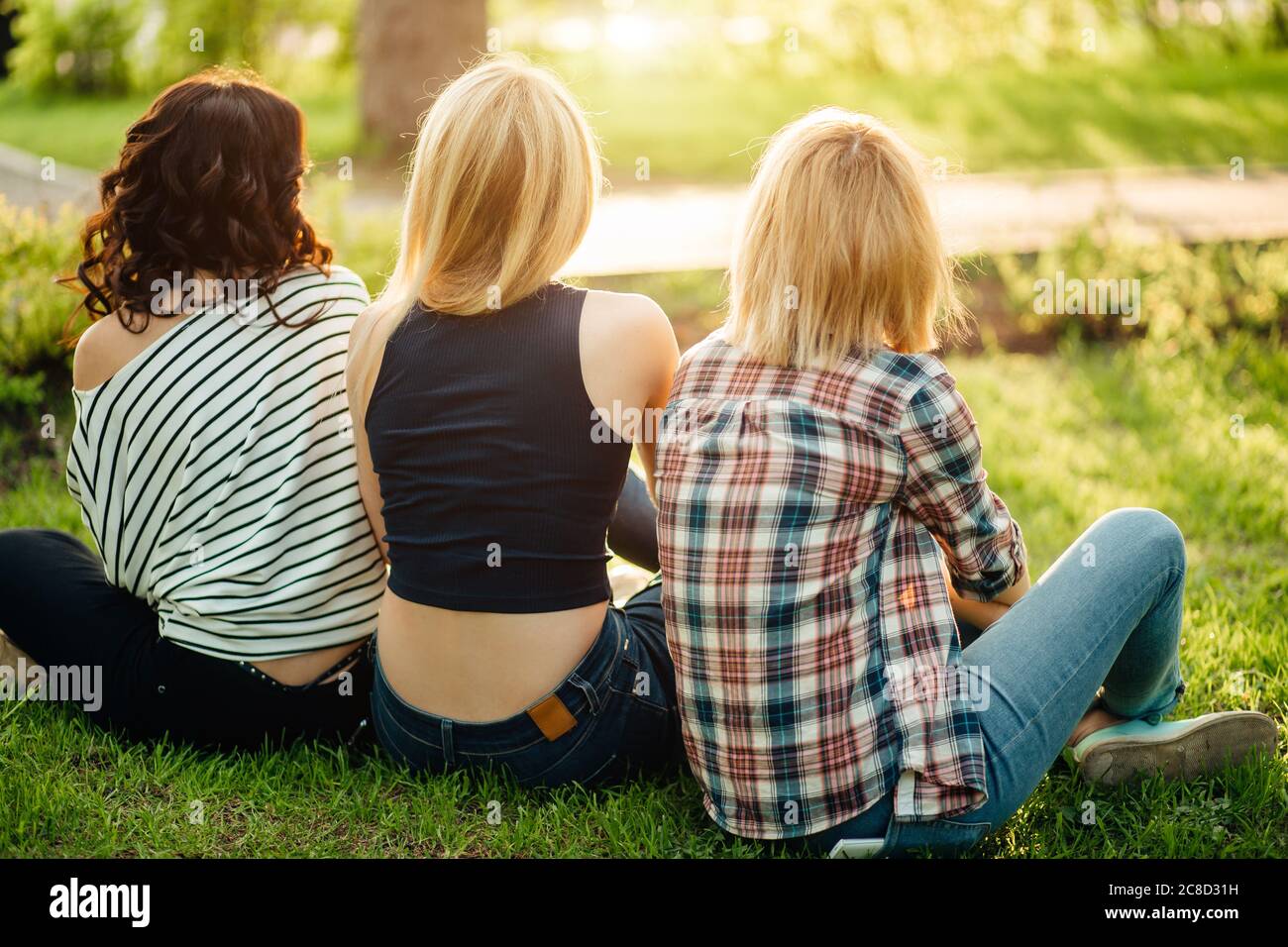 three girls having fun in the sunset park. rear view Stock Photo - Alamy