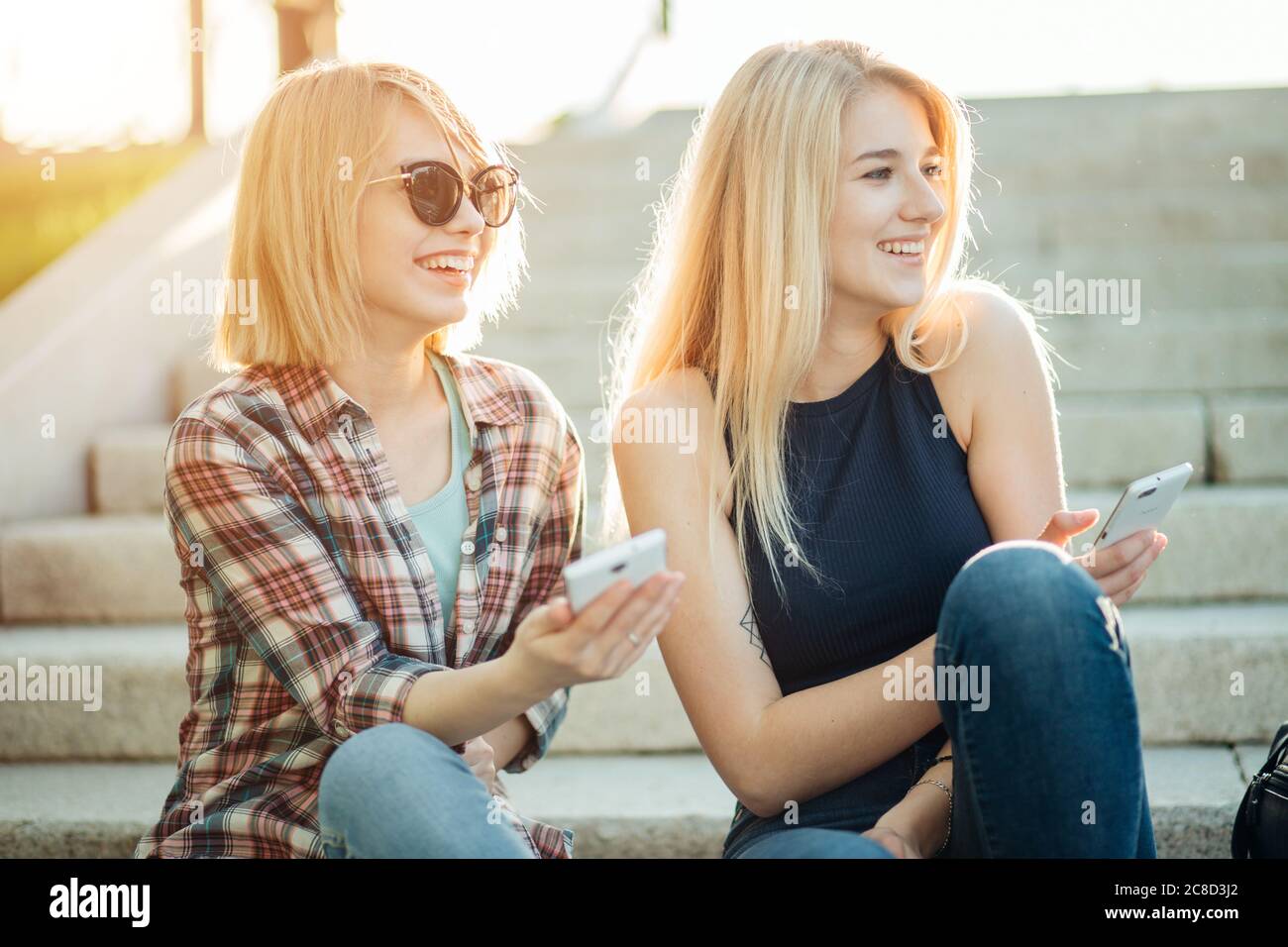 Two beautiful students watching media content on line in a smart phone ...