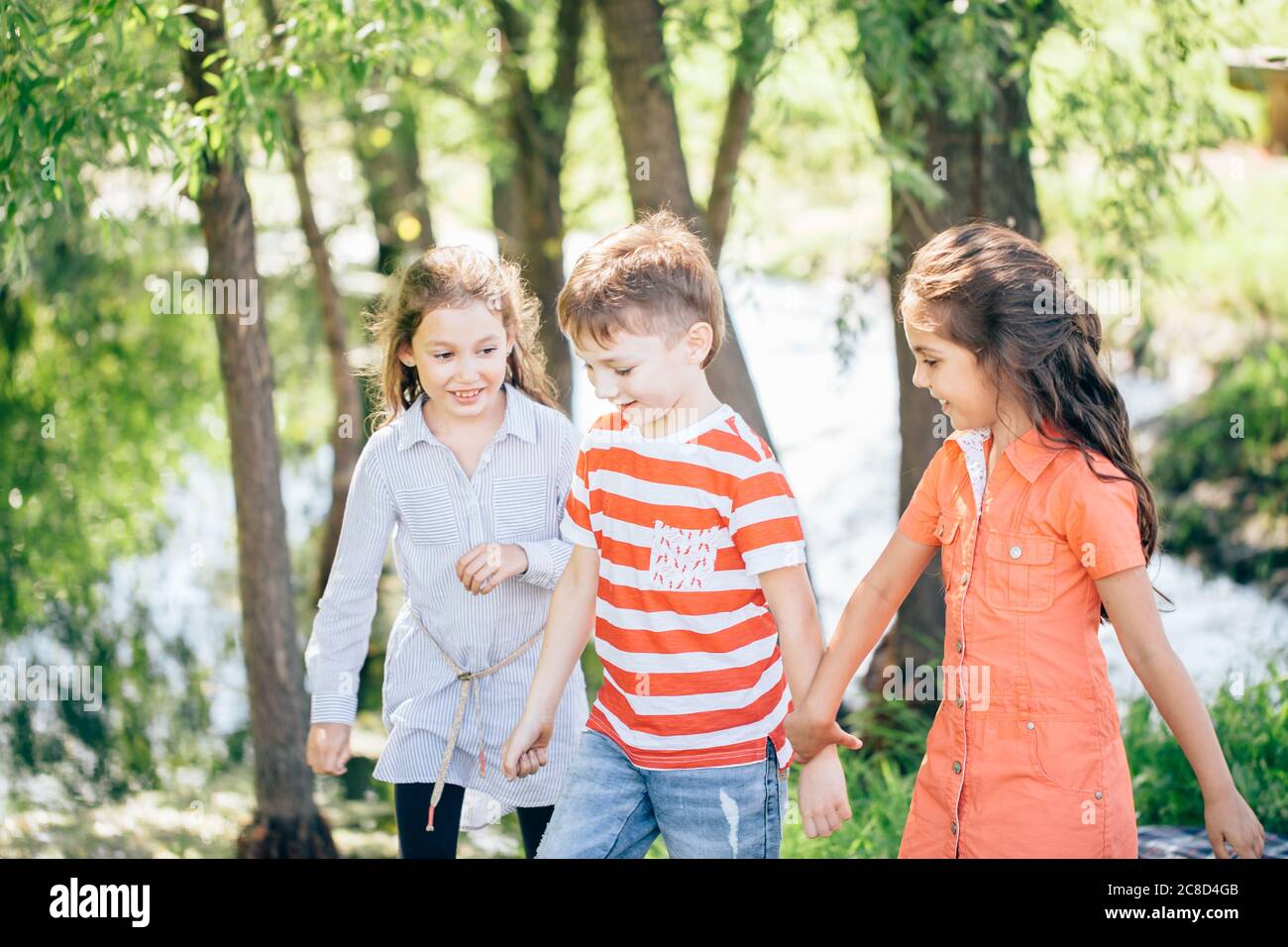 three happy children walking in park. Holding hands Stock Photo - Alamy