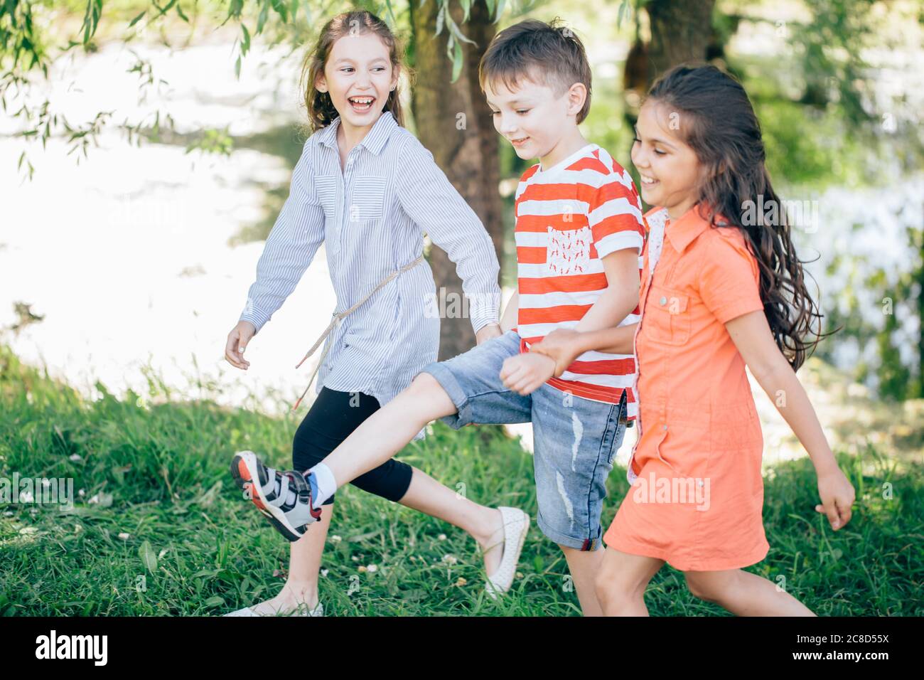 three happy children walking in park. Holding hands Stock Photo - Alamy